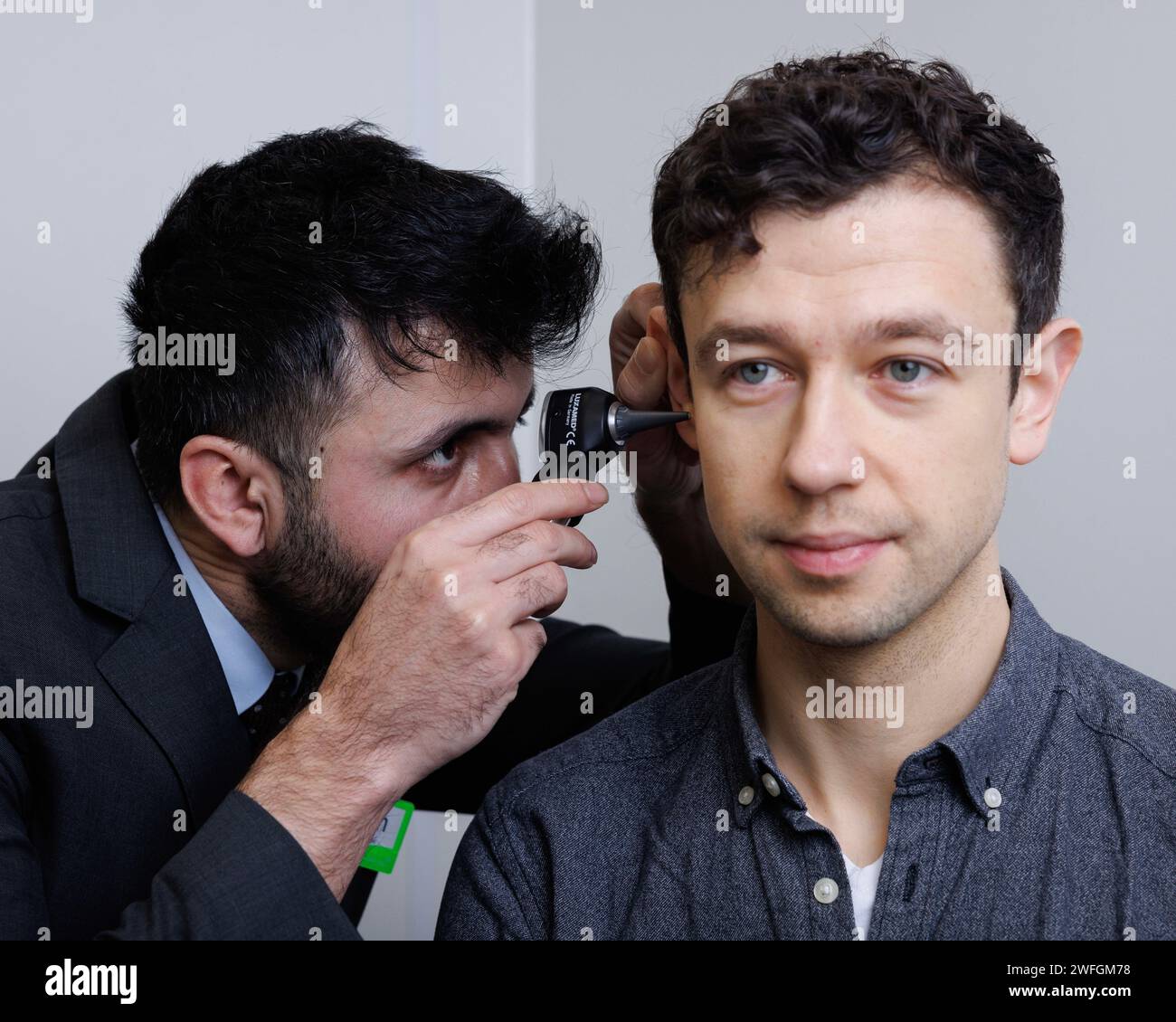 EDITORIAL USE ONLY Rahim Rahmani, Superdrug Pharmacist uses an otoscope ...