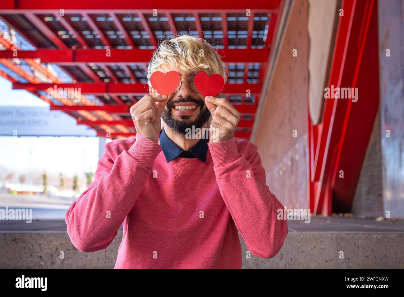 Portrait happy young man in love hiding her eyes behind paper hearts ...