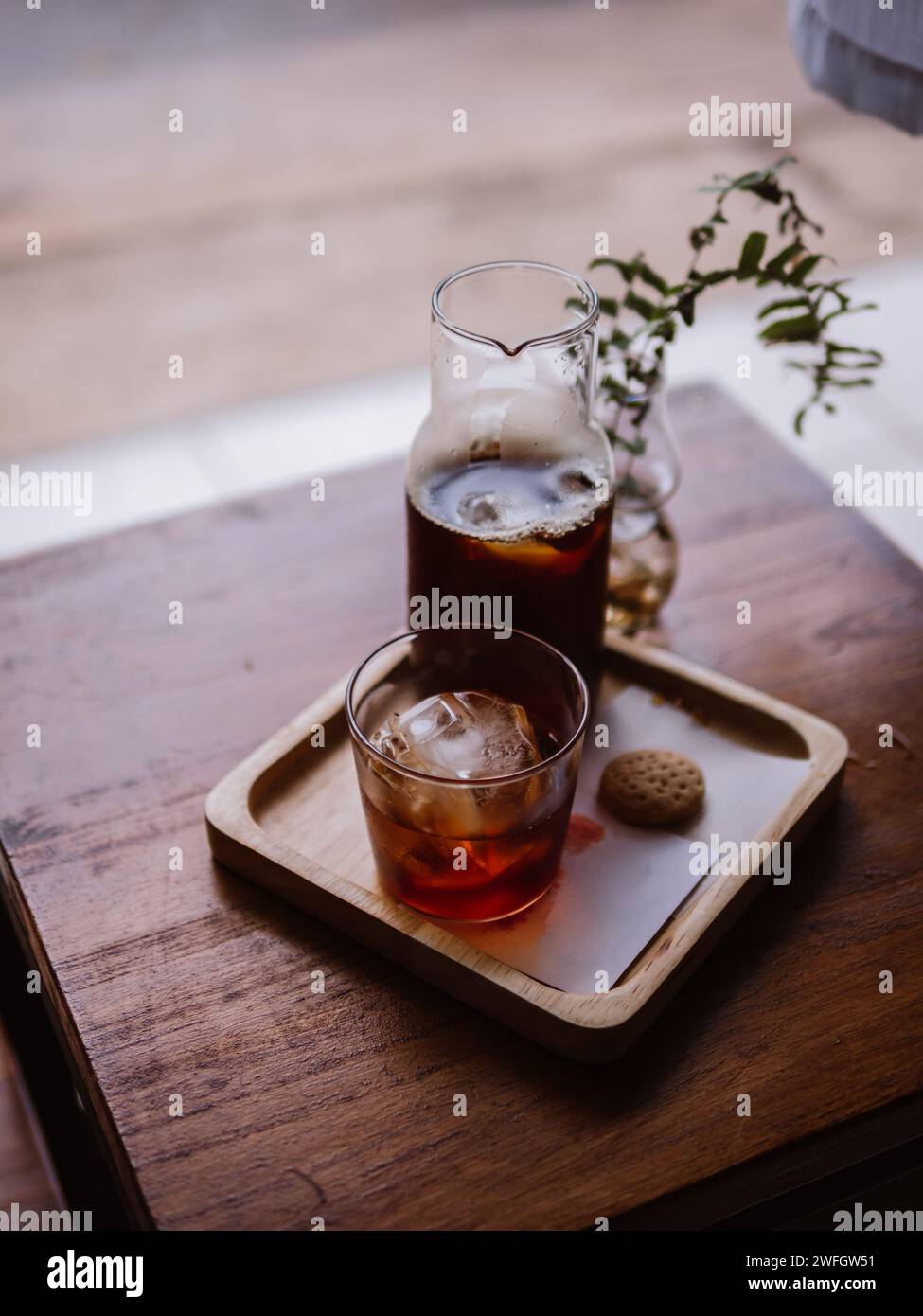Hand pouring coffee cold brew espresso ice coffee with ice cubes. Glass cold brew coffee with ...