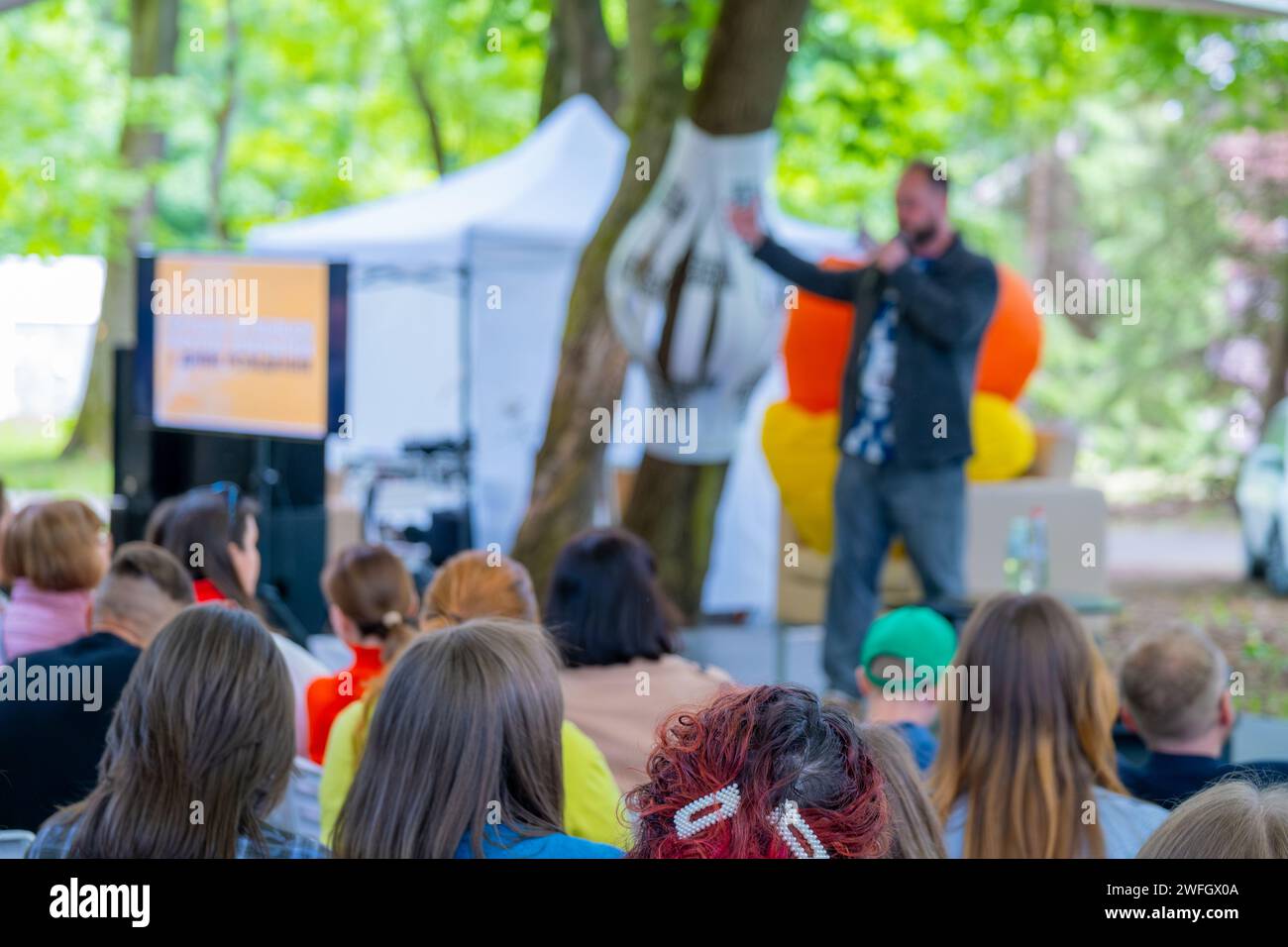 Outdoor presentation in a park setting with a diverse audience ...