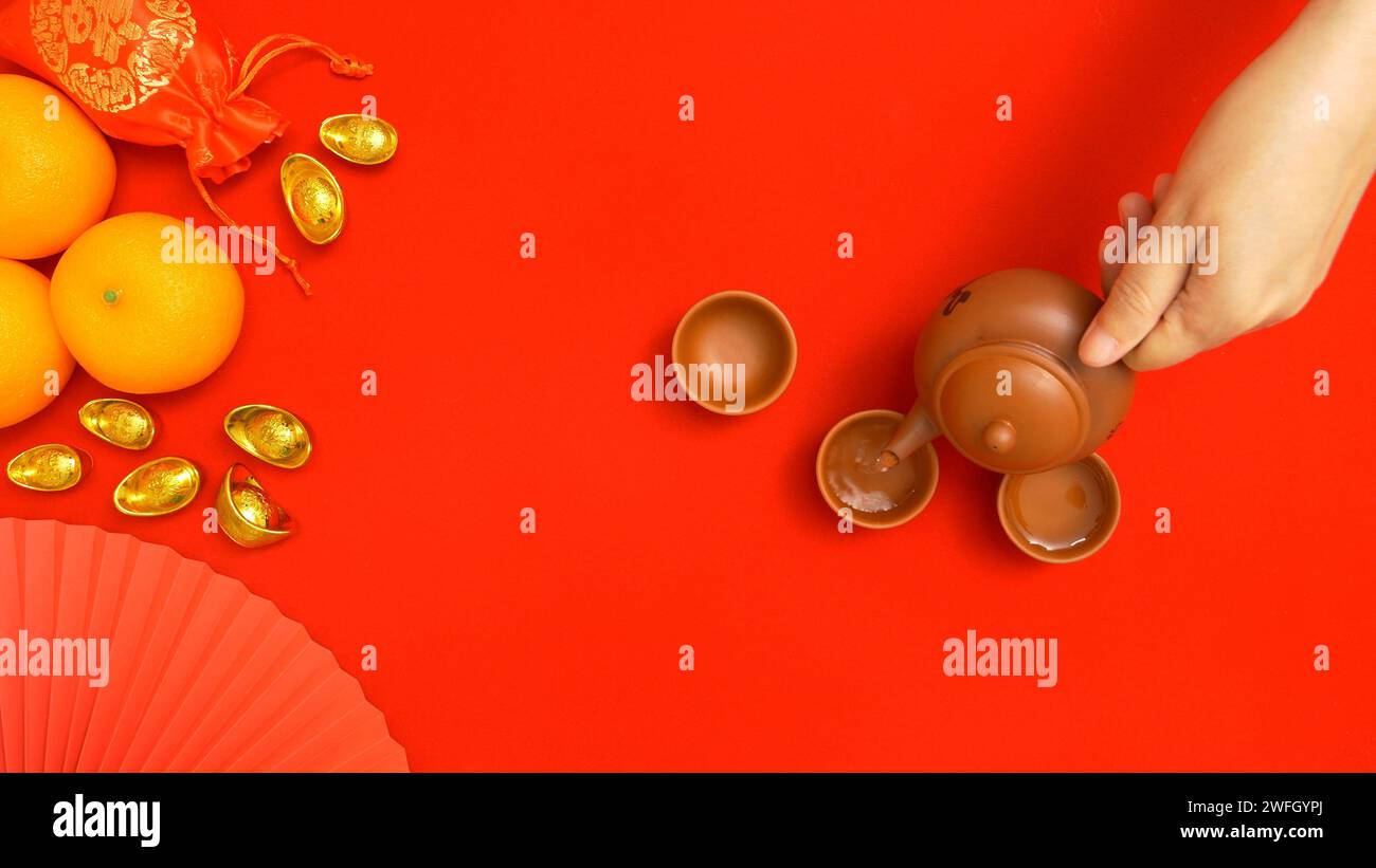 hand hold teapot to pouring tea into the teacup with orange, paper hand ...