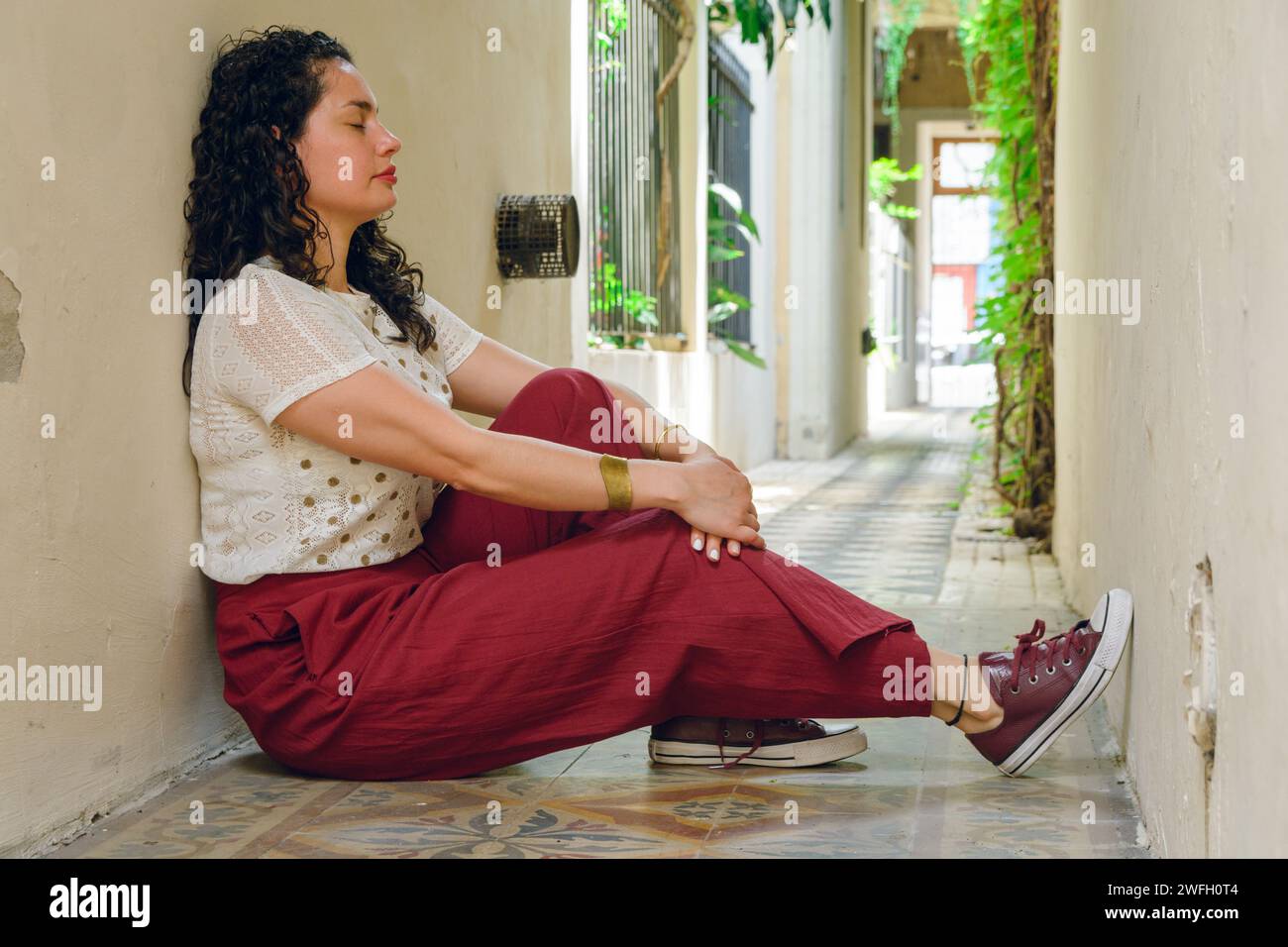 young latin business woman sitting in hallway of house sitting resting ...