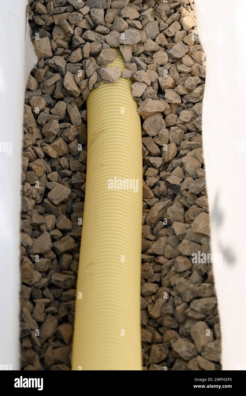 Yellow corrugated pipe with perforation in a trench with crushed stone ...