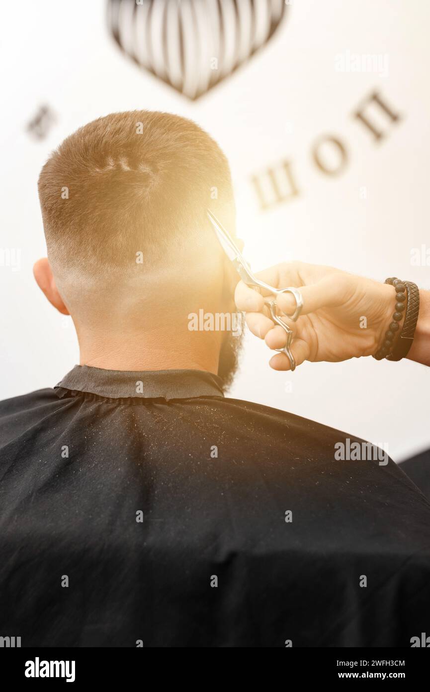Haircut and alignment of the contour of the head with scissors. Short ...