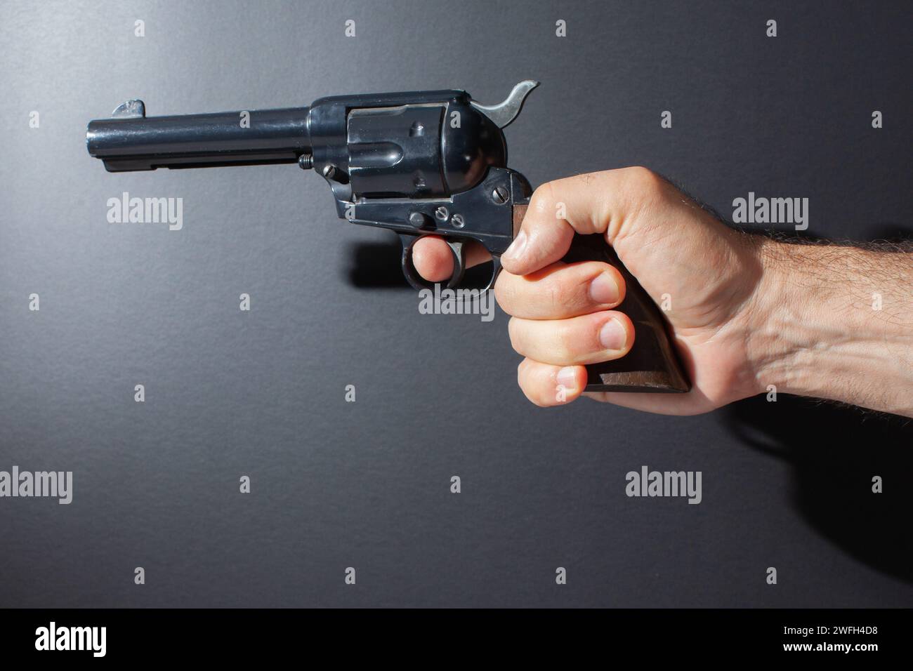hand holding replica gun isolated on dark background Stock Photo - Alamy