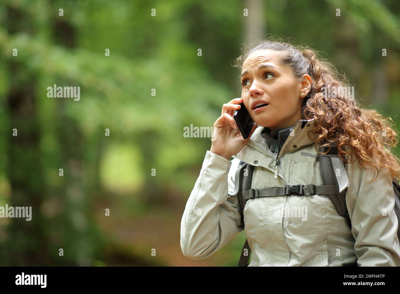 Worried lost hiker talking on phone walking in a forest Stock Photo - Alamy