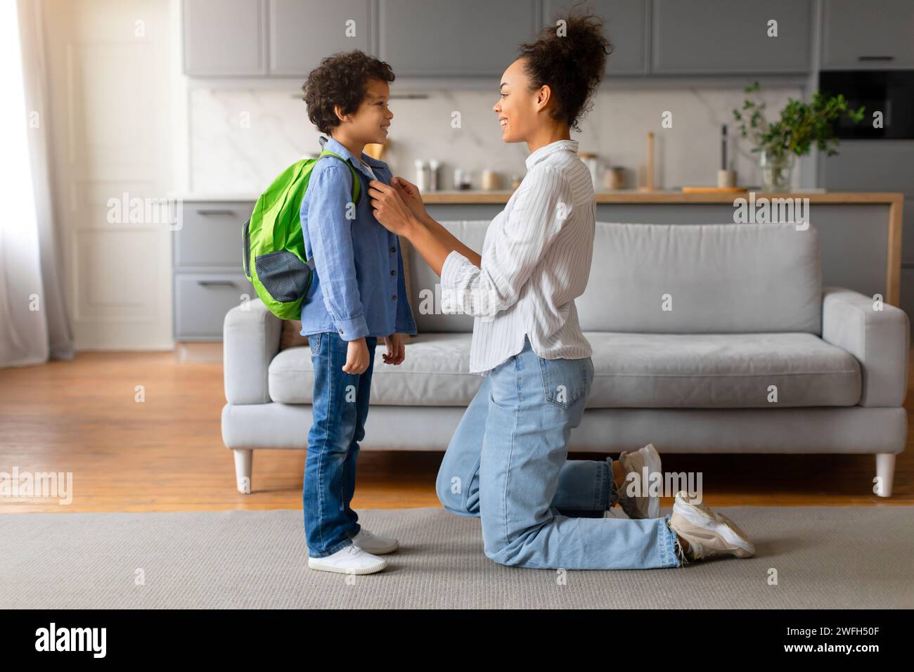 Mother adjusting son's backpack before school in living room Stock ...