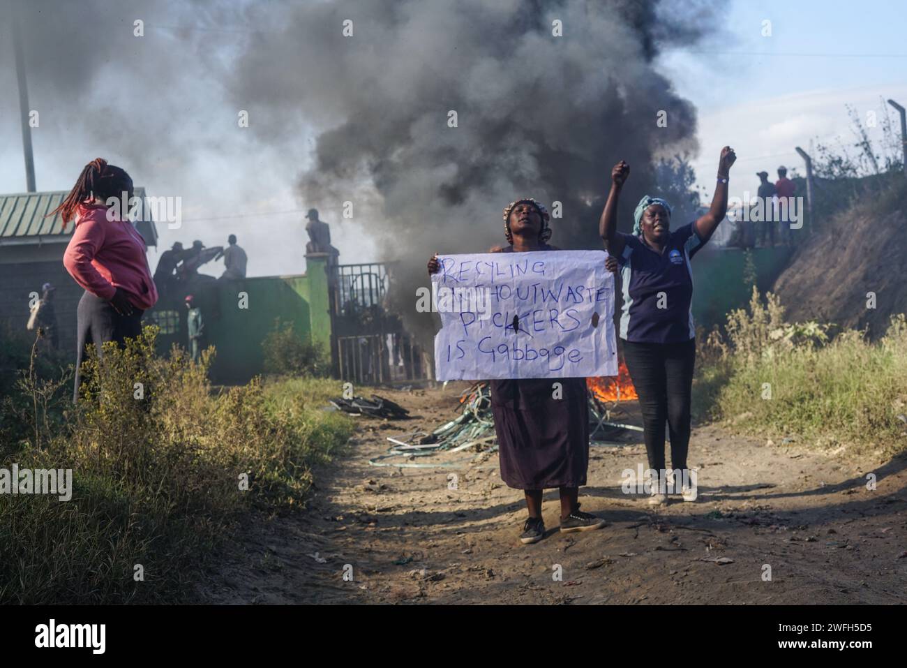 Waste pickers chant slogans in front of a smoky bonfire during a ...
