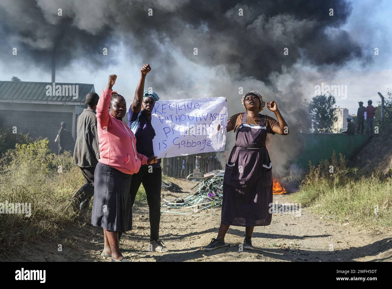 Waste pickers chant slogans in front of a smoky bonfire during a ...