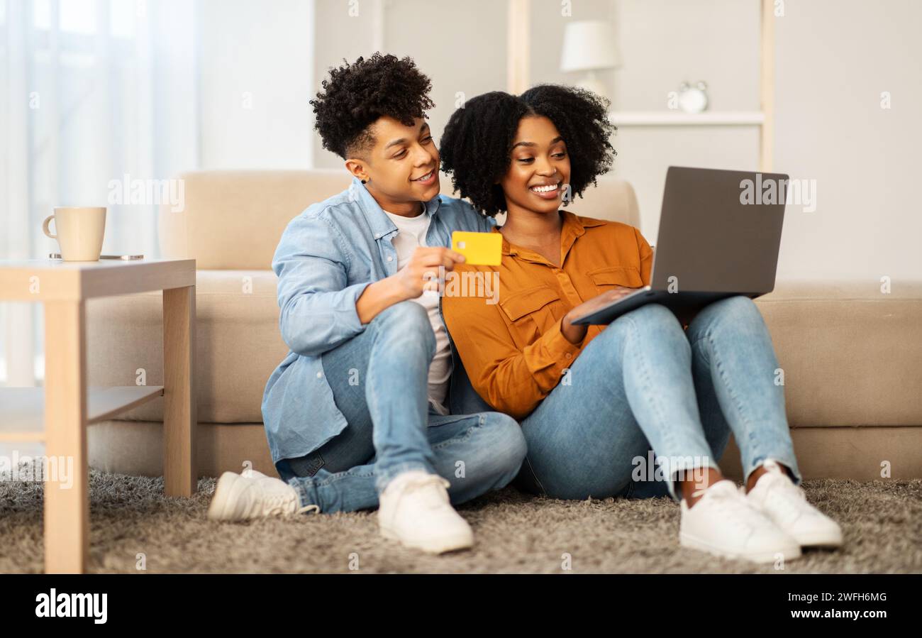 A content couple sits on the floor with technology at their fingertips ...