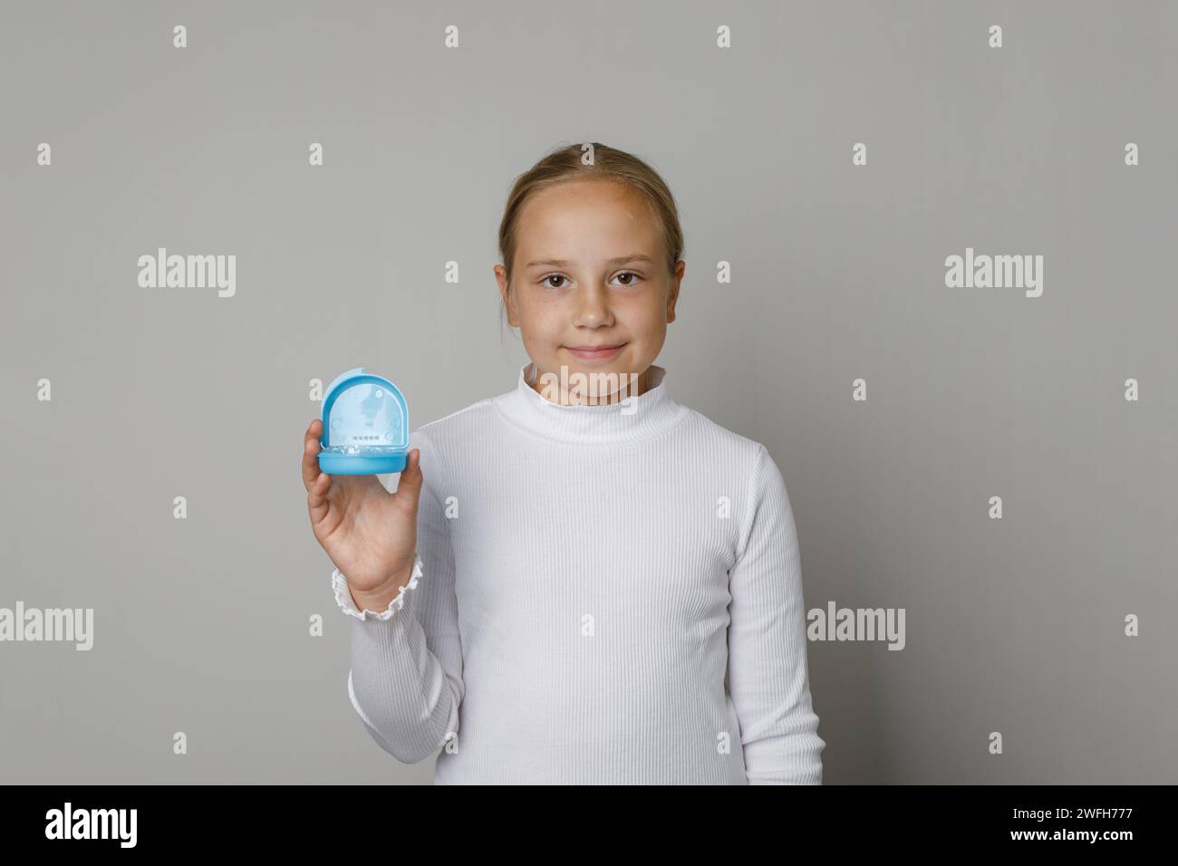 Happy young child girl holding invisalign transparent retainers with a ...