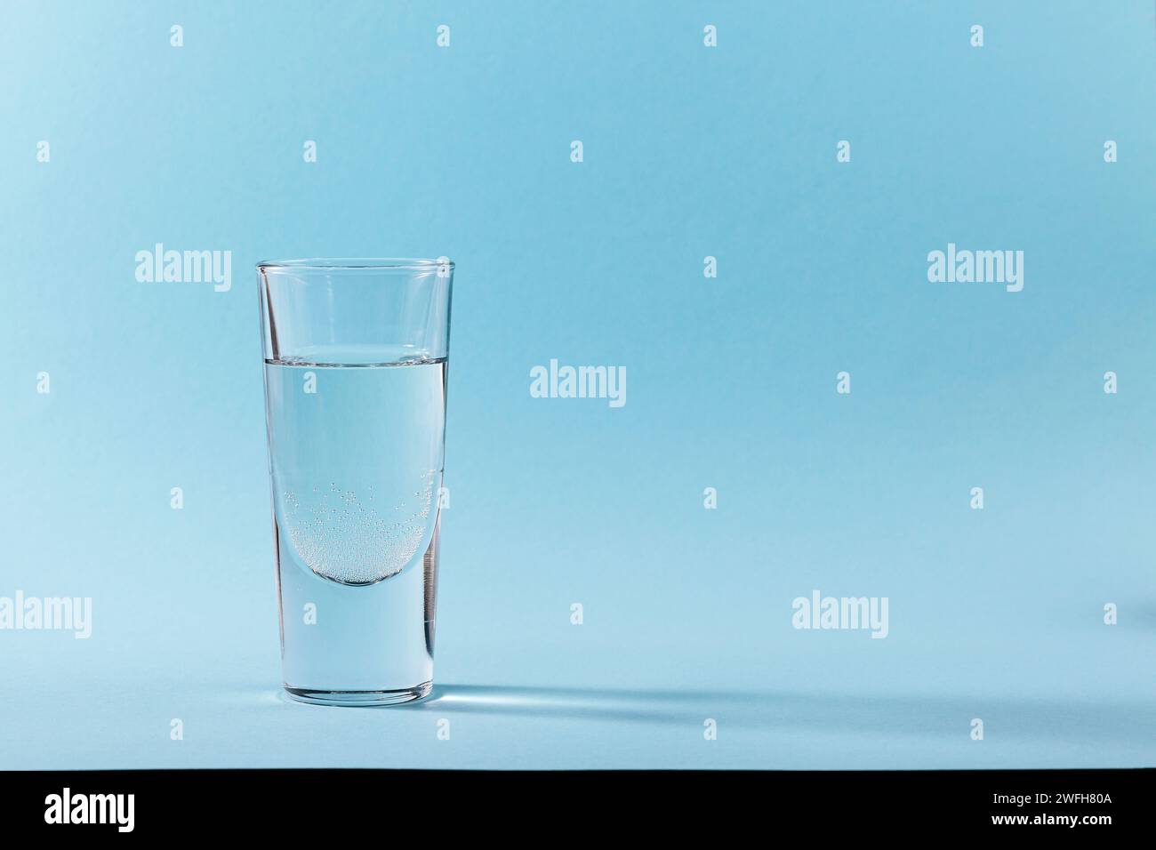 Glass of pure sparkling water on light blue background Stock Photo - Alamy
