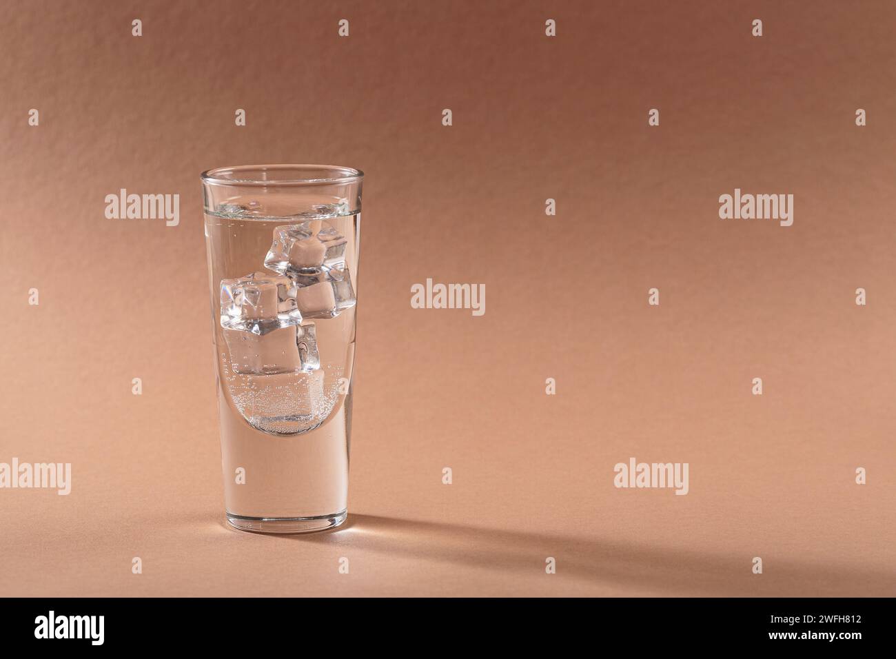 Glass of pure cold sparkling water with ice cubes on light brown background Stock Photo - Alamy