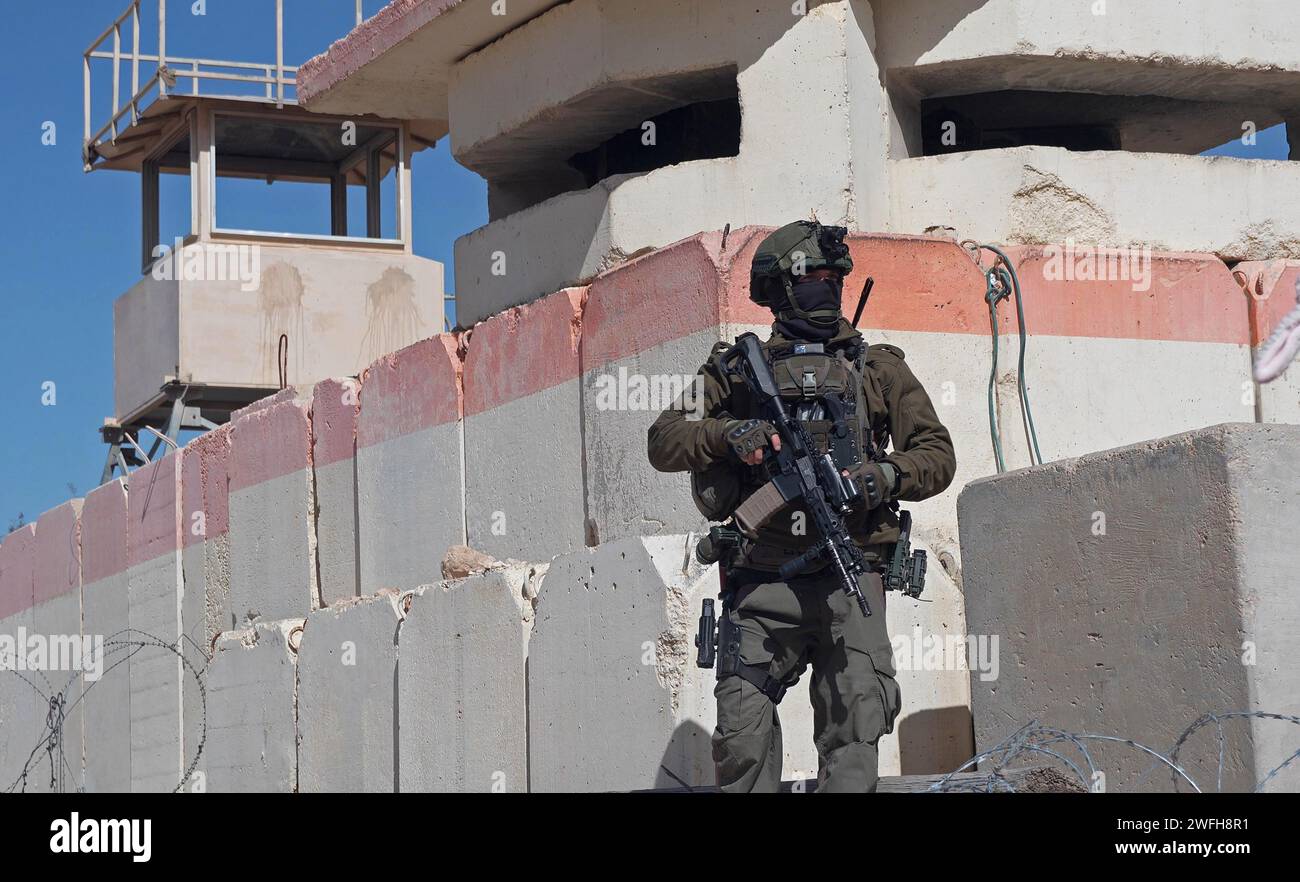 An Israeli soldier stands guard at the Nitzana crossing where trucks ...