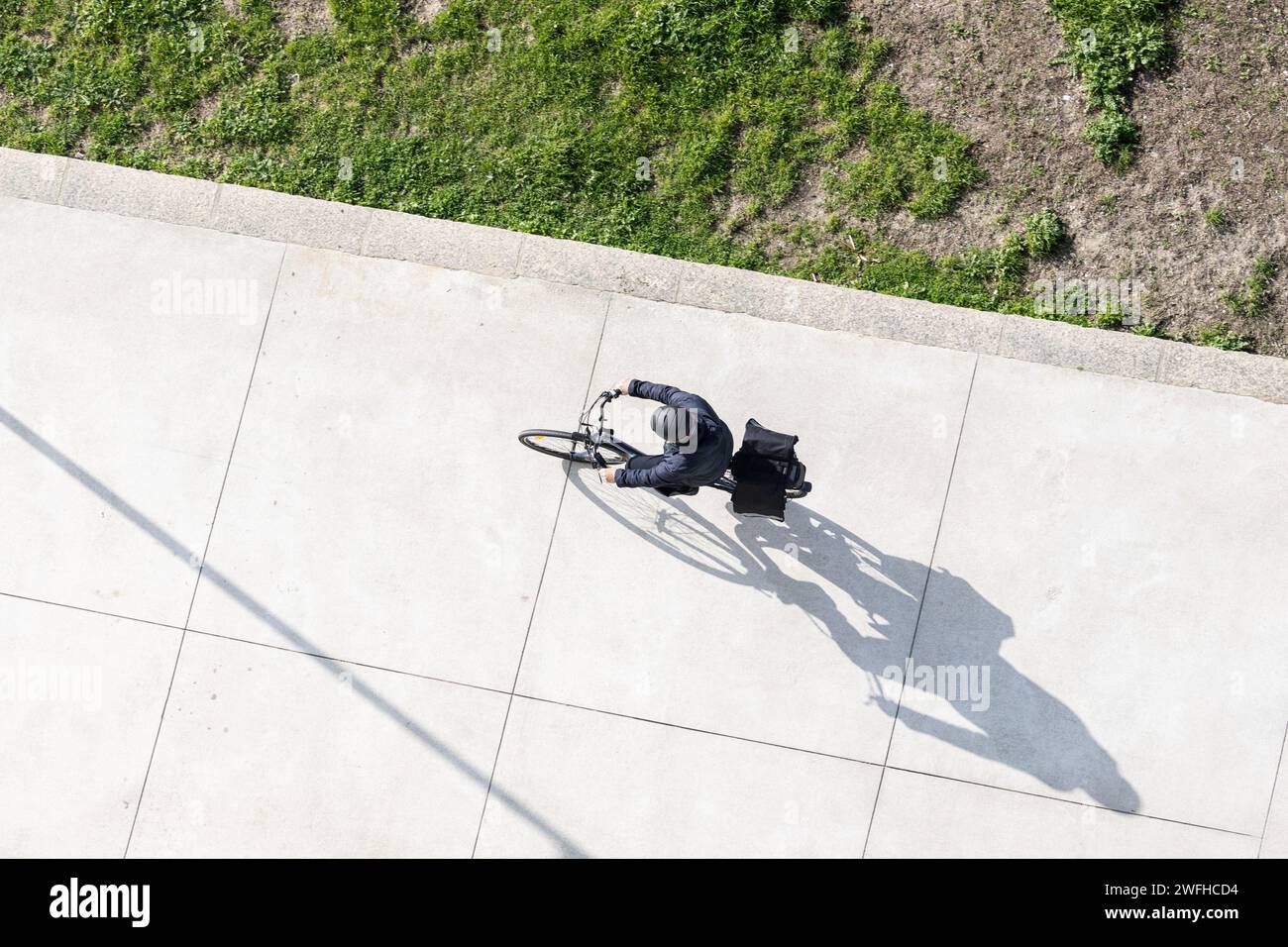 Cyclist with helmet riding a electric bicycle on a concrete way. Copy ...