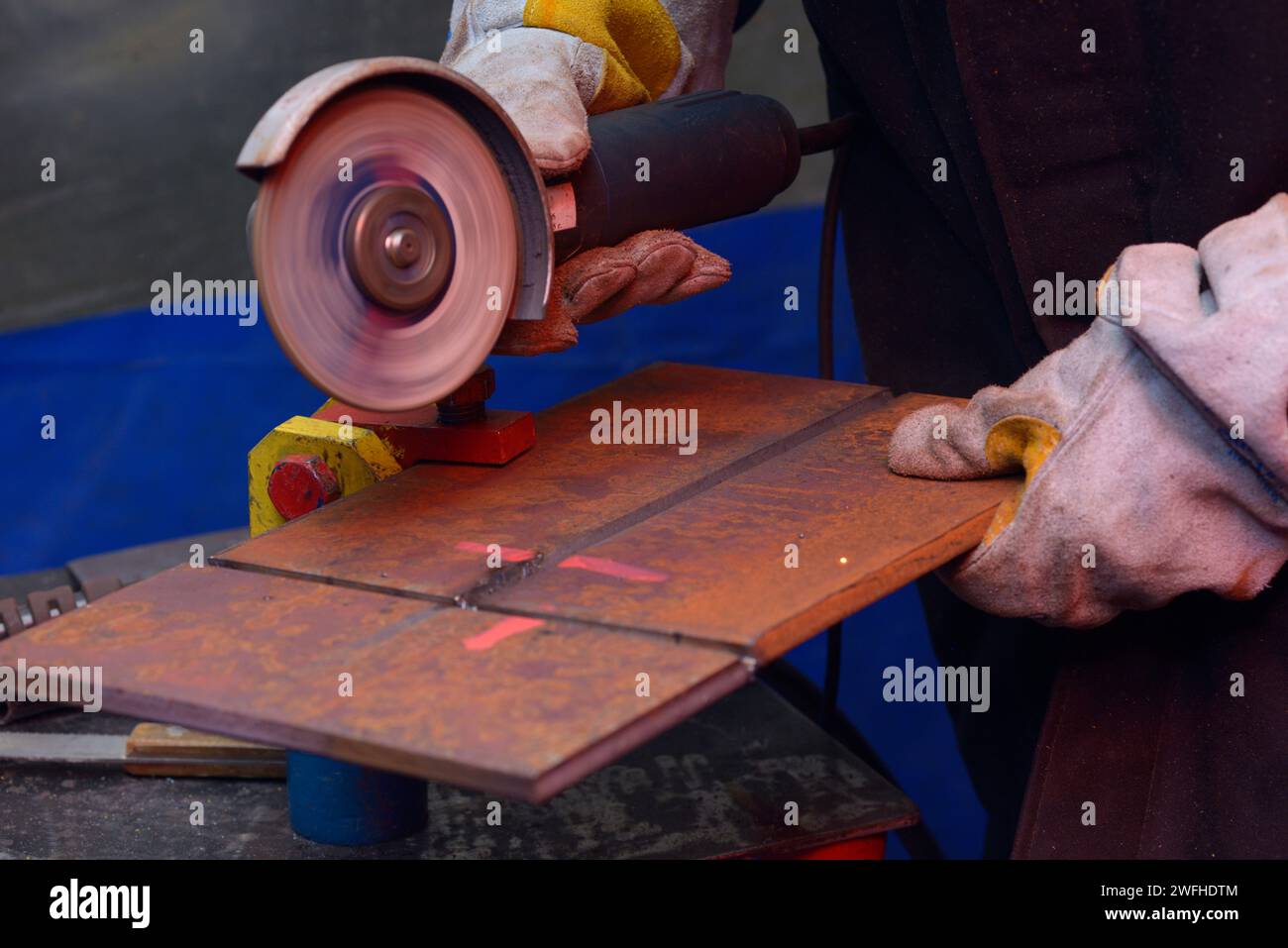 Welder hands grinding metal piece with a grinder, processing weld after ...