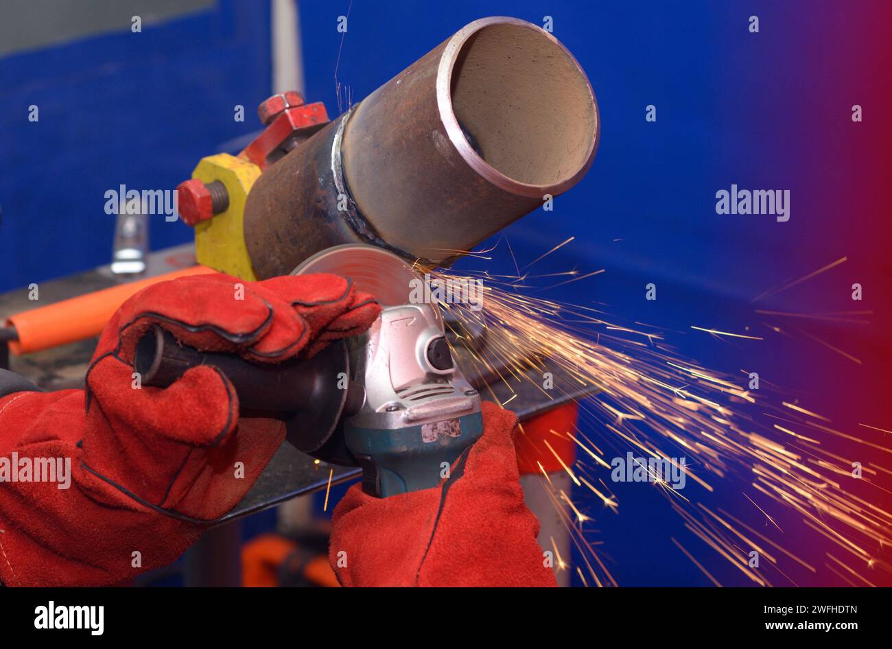 Welder hands grinding metal piece with a grinder, processing weld after ...