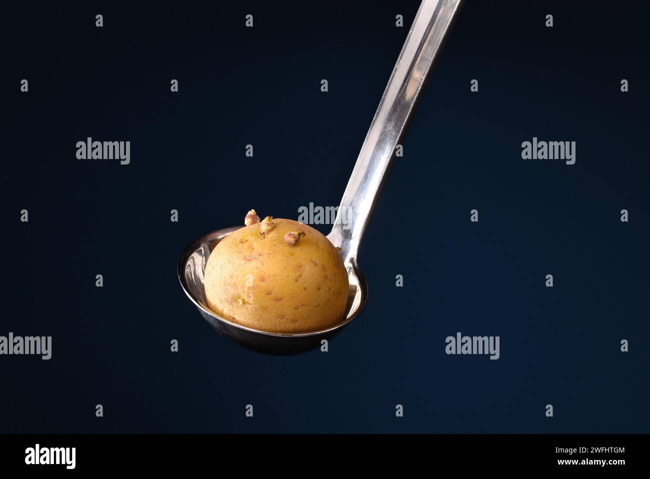Potato in ladle on dark blue background Stock Photo - Alamy
