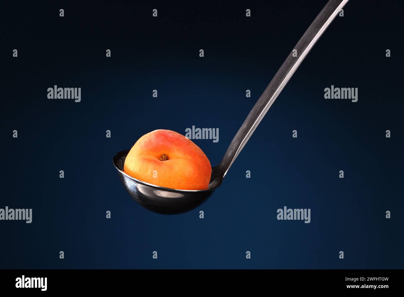 Apricots in ladle on dark blue background Stock Photo - Alamy