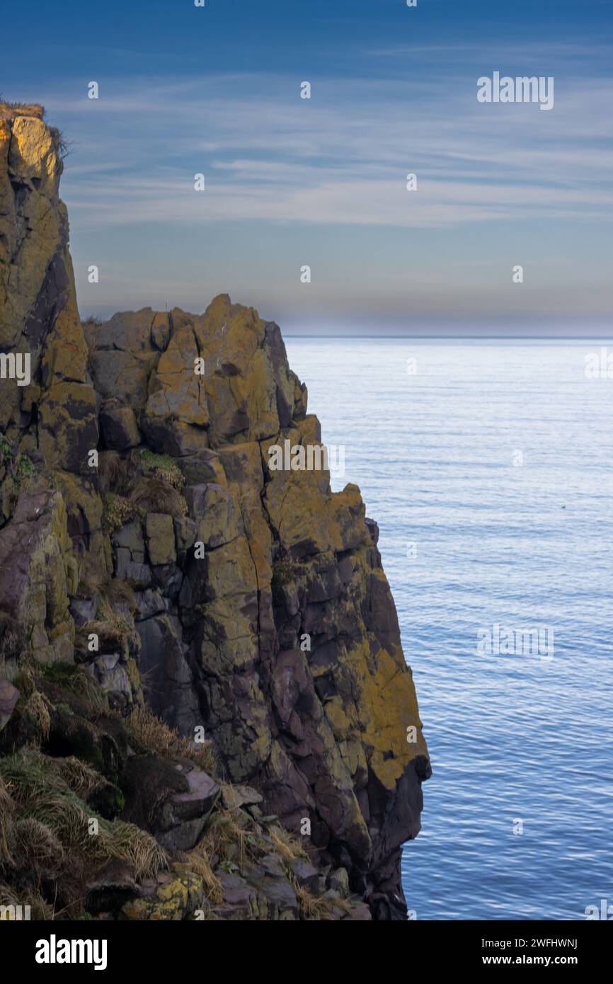 Sharp edges of a rock with spots of moss and lichen. Blue sky with ...