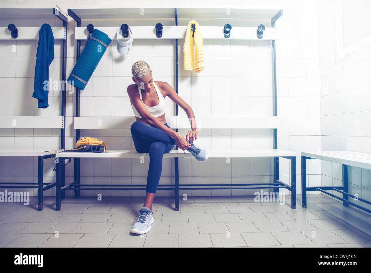 In the locker room, a sporty African American female athlete prepares ...