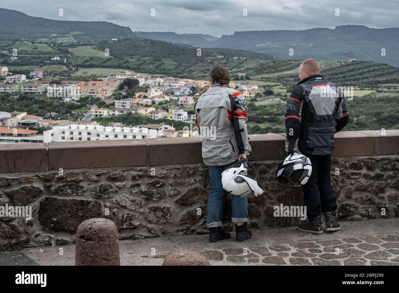 Rear view of two men looking over a ledge at the landscape Castelsardo ...