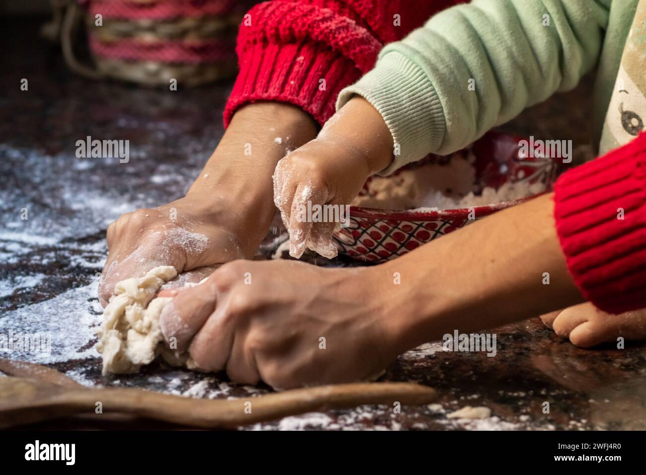 Close-up of little girl hands cooking with her mother at home. Kneading ...