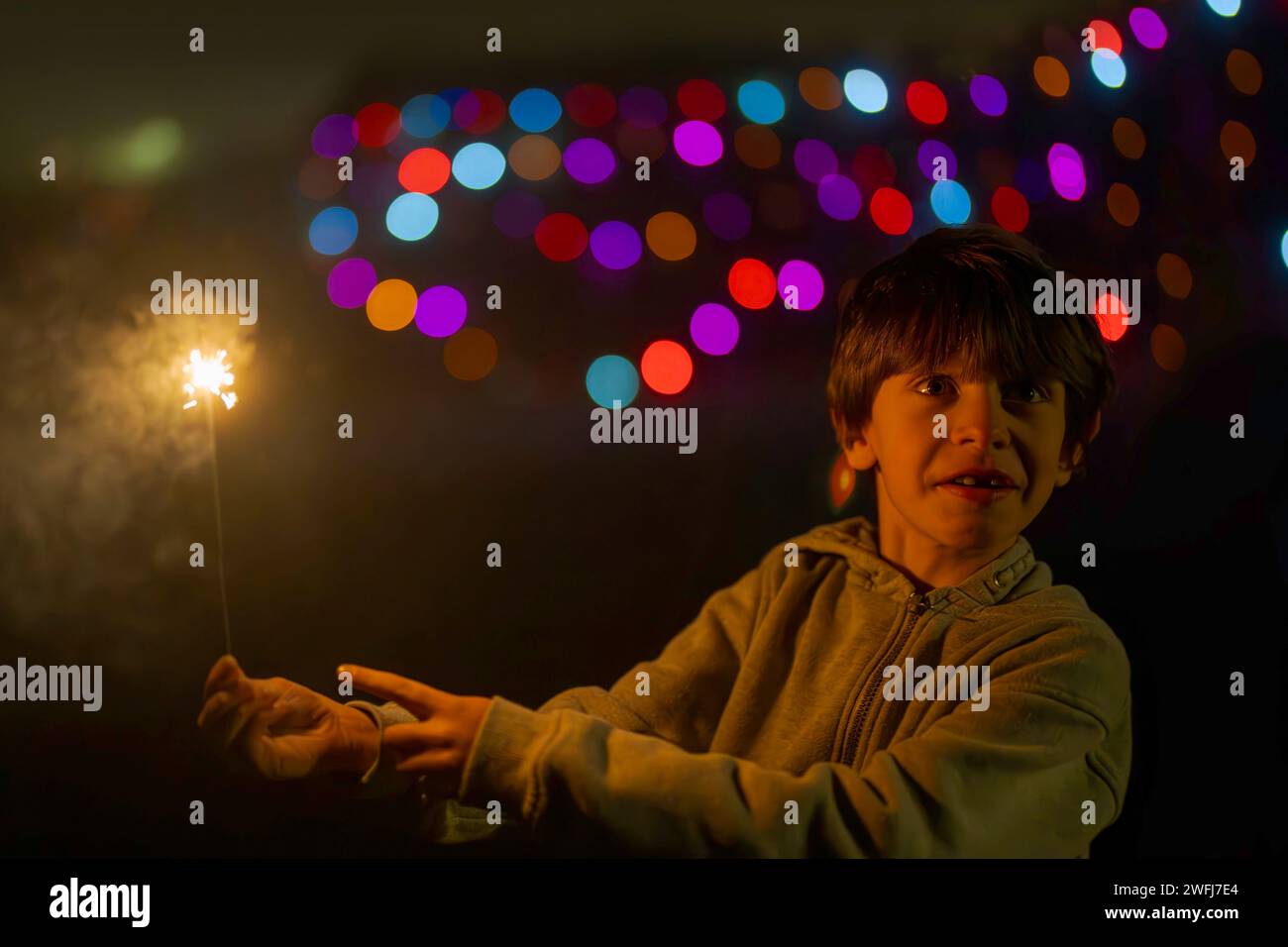 Cute boy holding fireworks, looking excited Stock Photo - Alamy