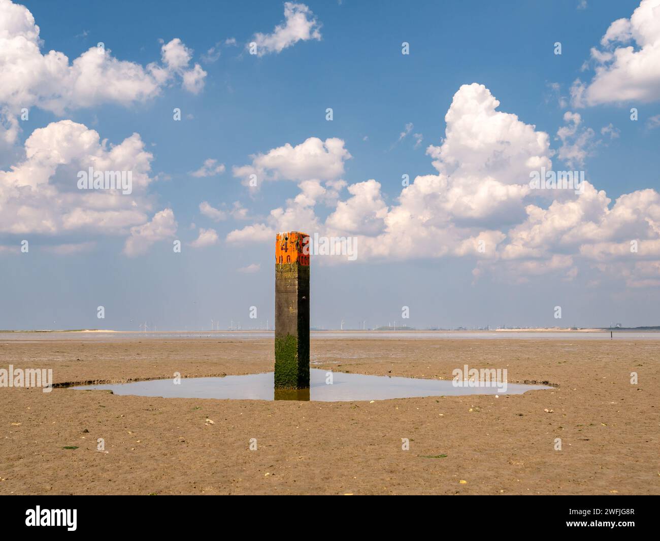 Wooden beach pole with red top in puddle at low tide - distance marker ...