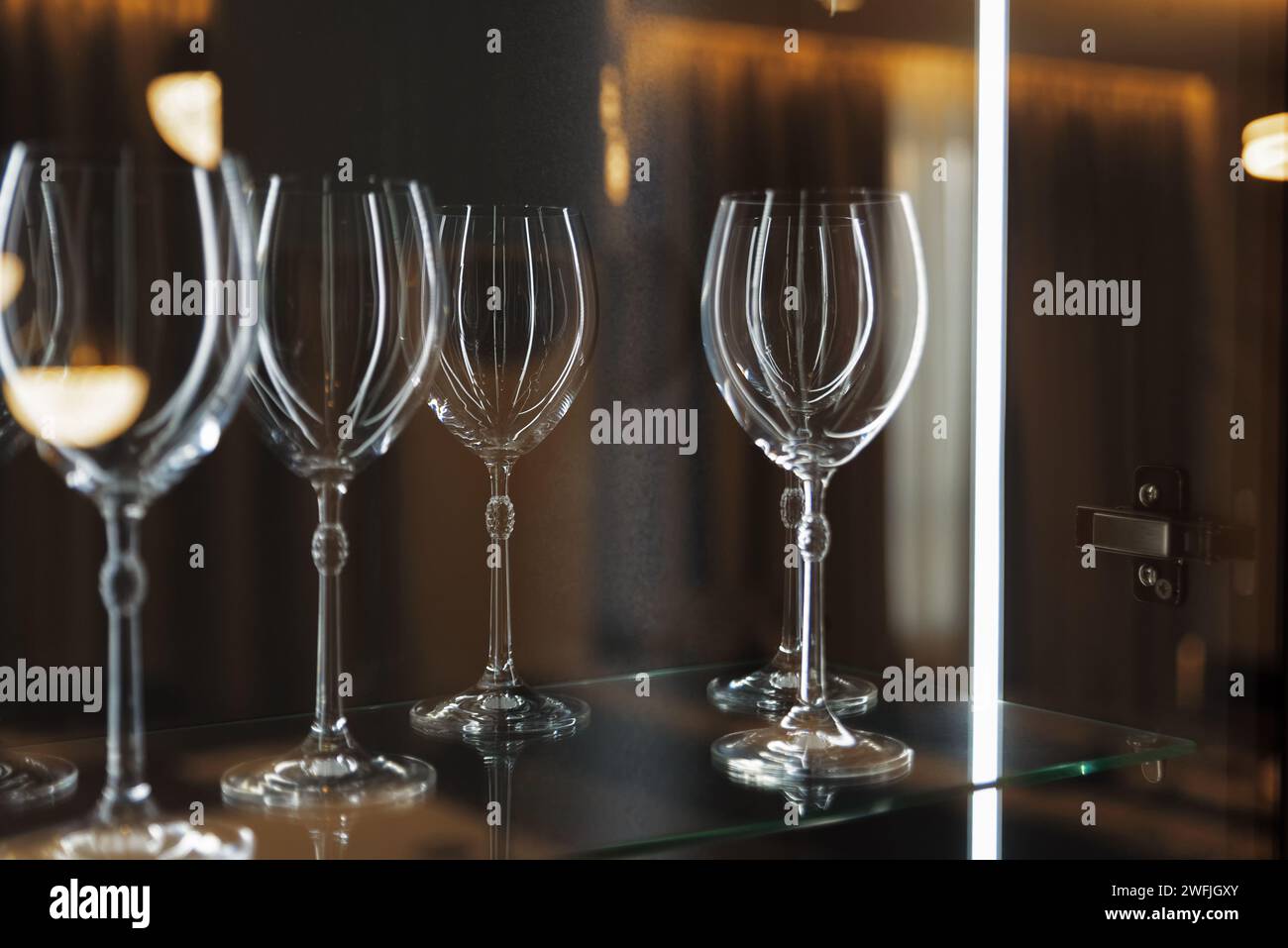 Wine glasses on a glass shelf with lighting. Empty crystal glasses ...