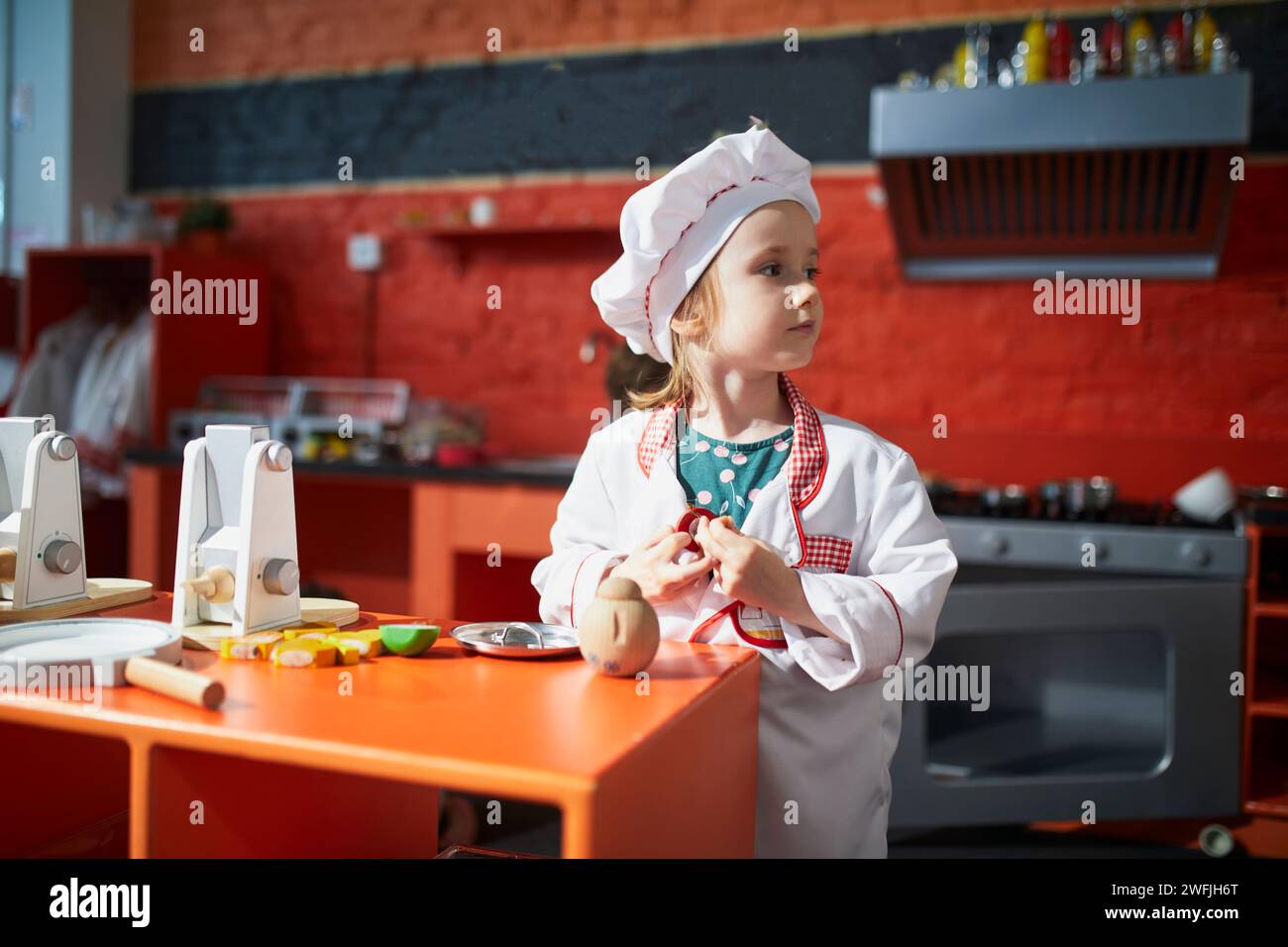 Adorable preschooler girl playing cook at the kitchen or in restaurant ...