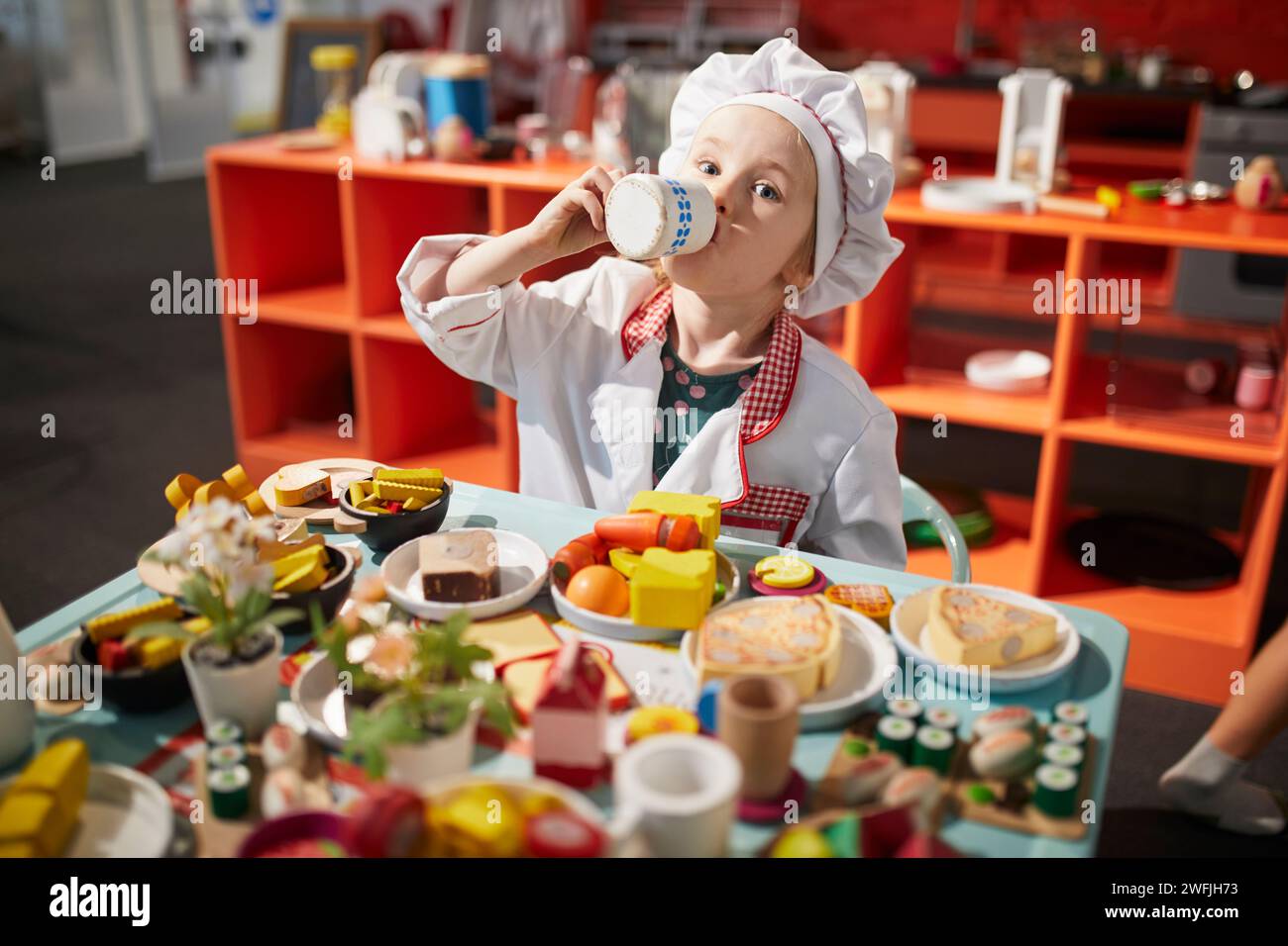 Adorable preschooler girl playing cook at the kitchen or in restaurant ...