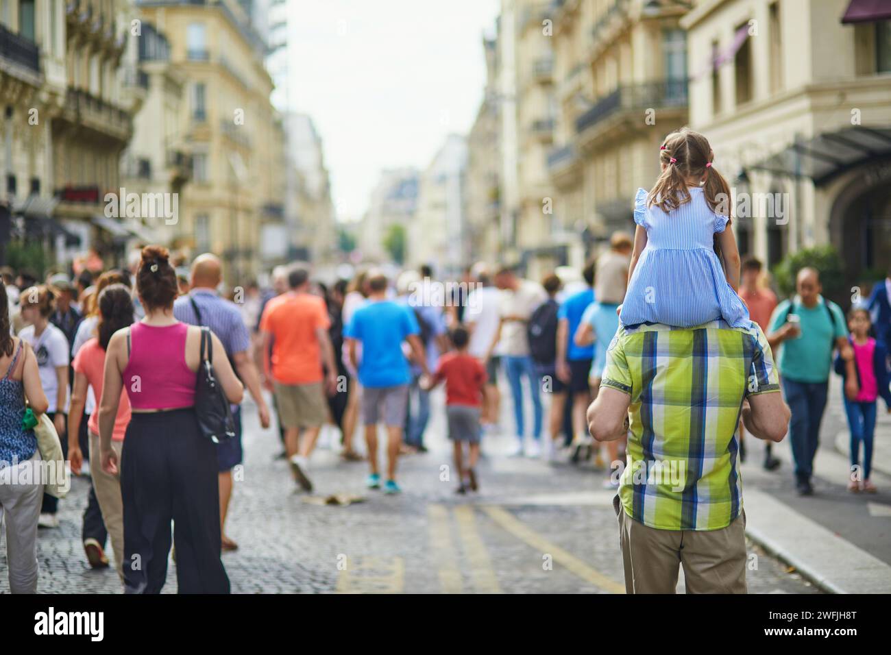 Father holding his daughter on shoulders and walking on a street of ...
