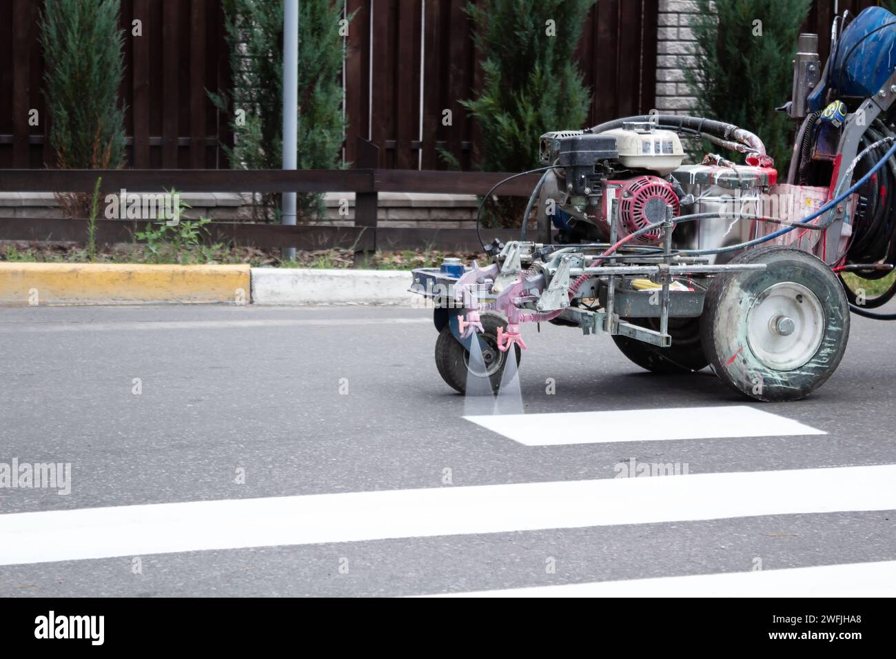 City workers paint crosswalk lanes on the road. Painting machine paints ...