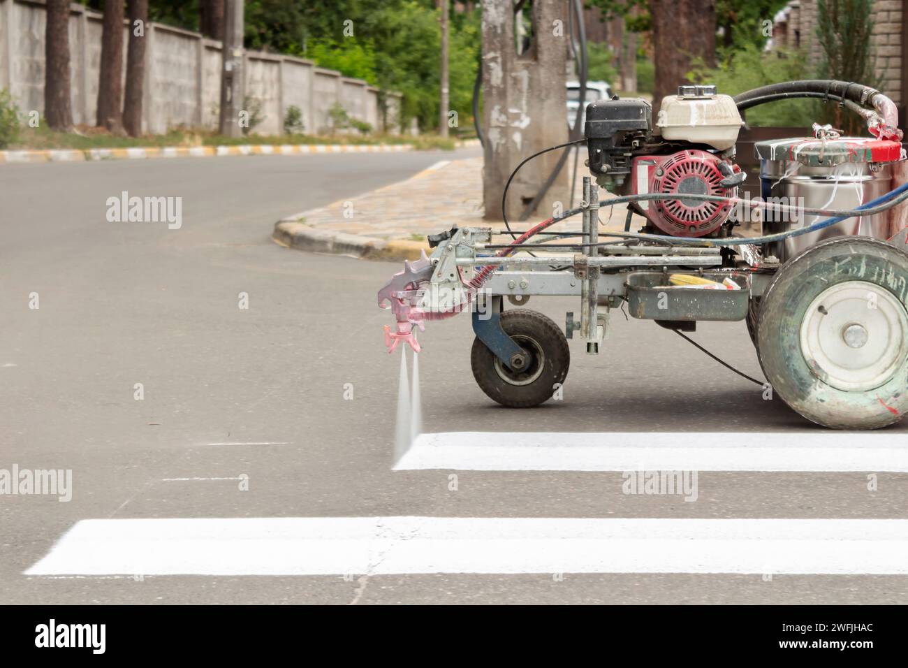 City workers paint crosswalk lanes on the road. Painting machine paints ...