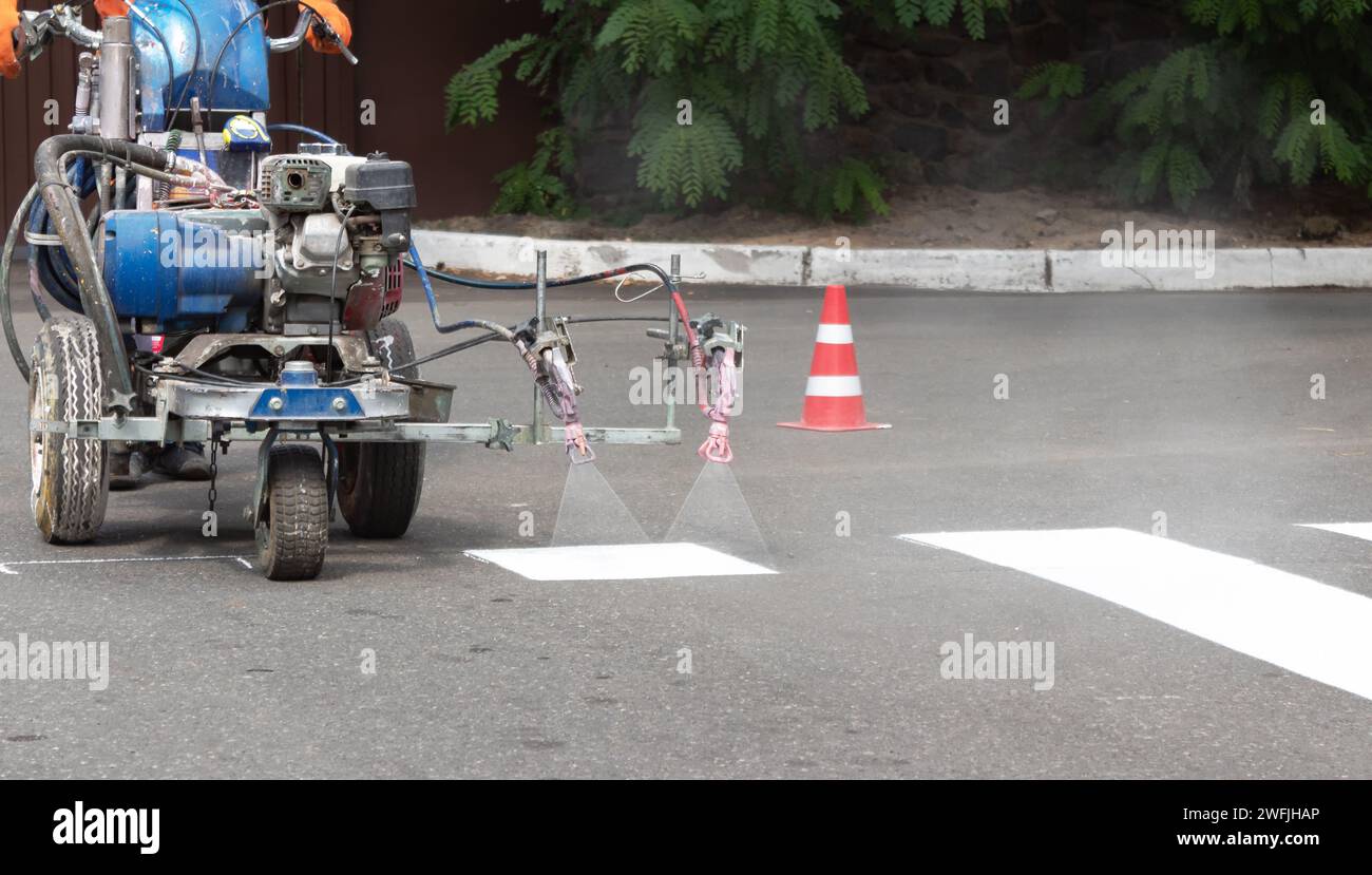 City workers paint crosswalk lanes on the road with painting machine ...