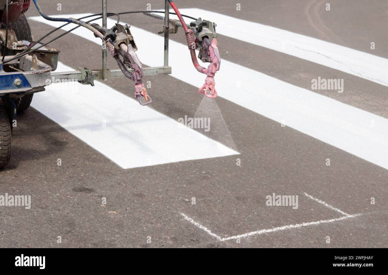 City workers paint crosswalk lanes on the road. Painting machine paints ...