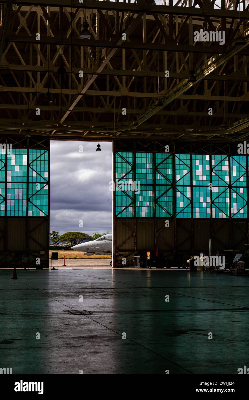 A fighter jet parked in front of the entrance of an aircraft hanger ...