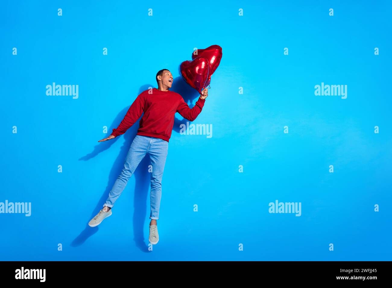 Full size portrait of astonished excited man hold heart figure balloons ...