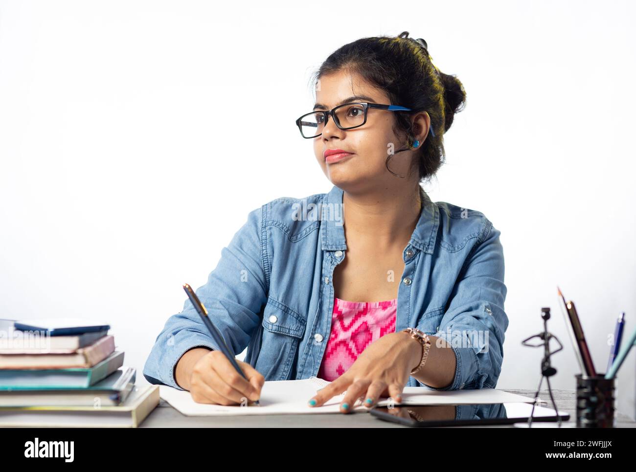 A pretty young Indian college student in eyeglasses studying and ...