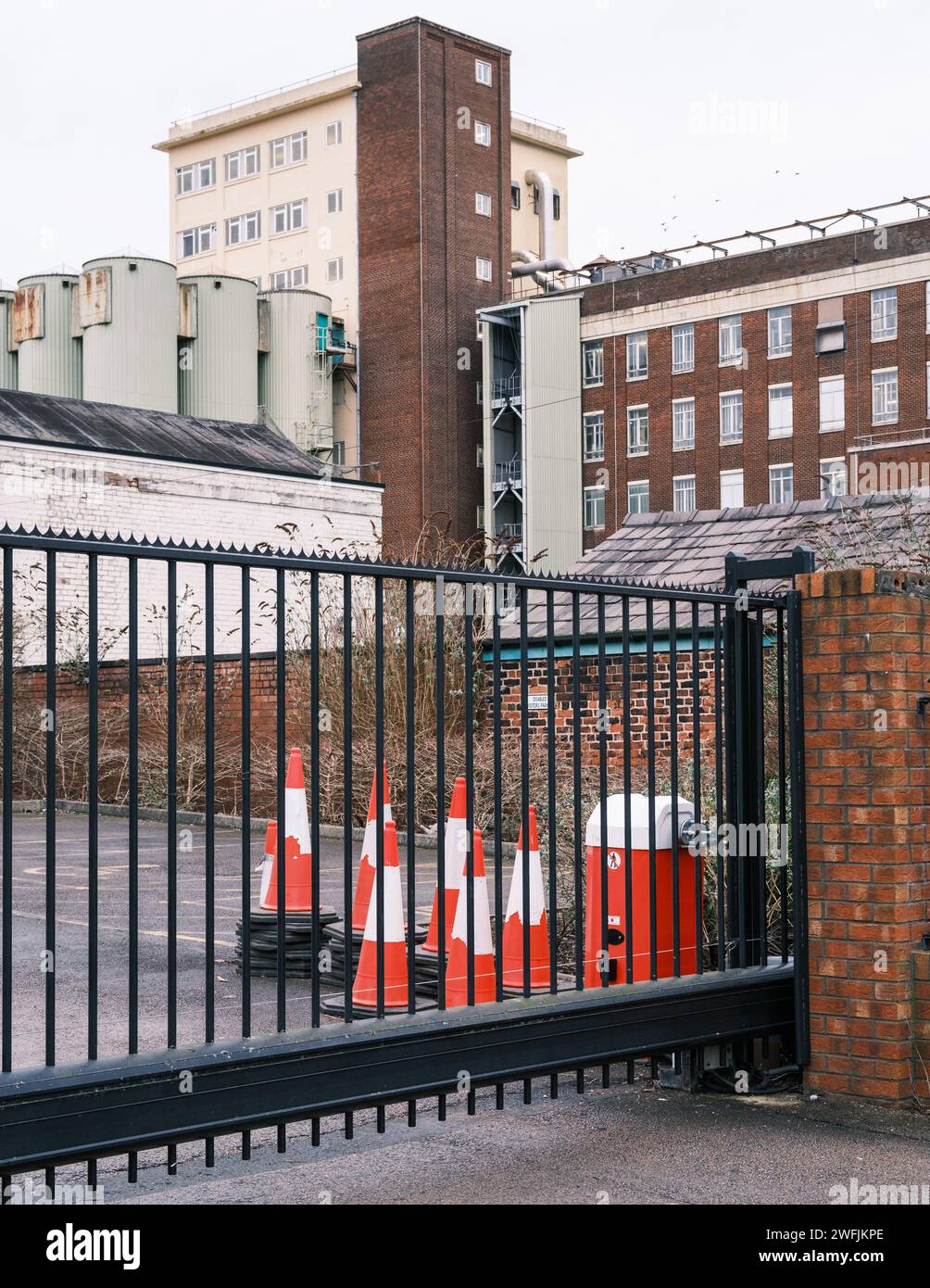 metal gates at the factory entrance closed with a pile of traffic cones ...