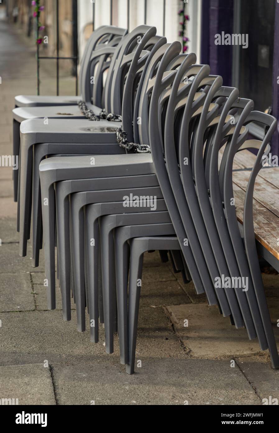 Pile of stacking silver gray plastic chairs are beside of The cafe ...