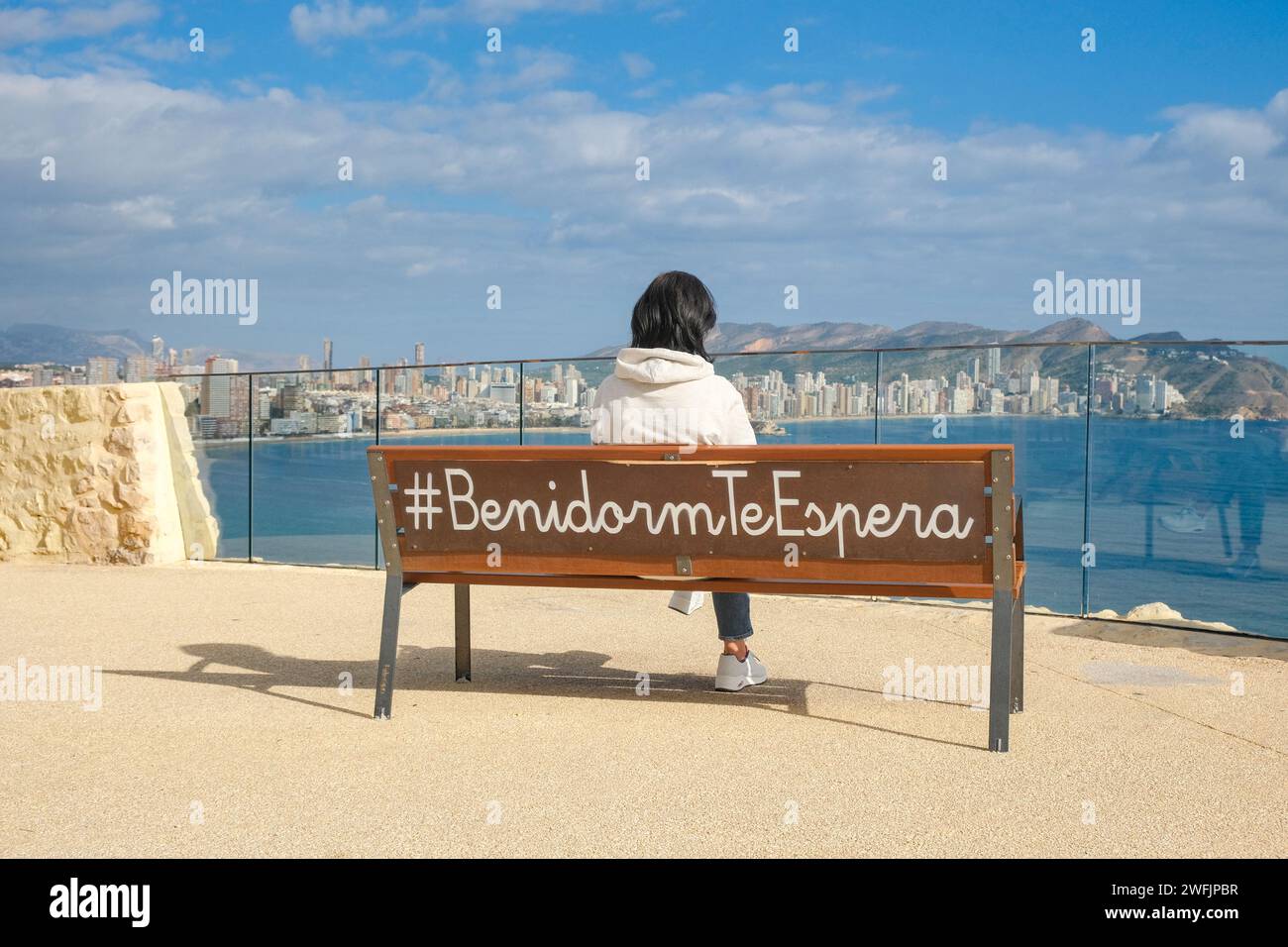 Woman sitting on bench in Benidorm city viewpoint with Benidorm city and Mediterranean sea ...