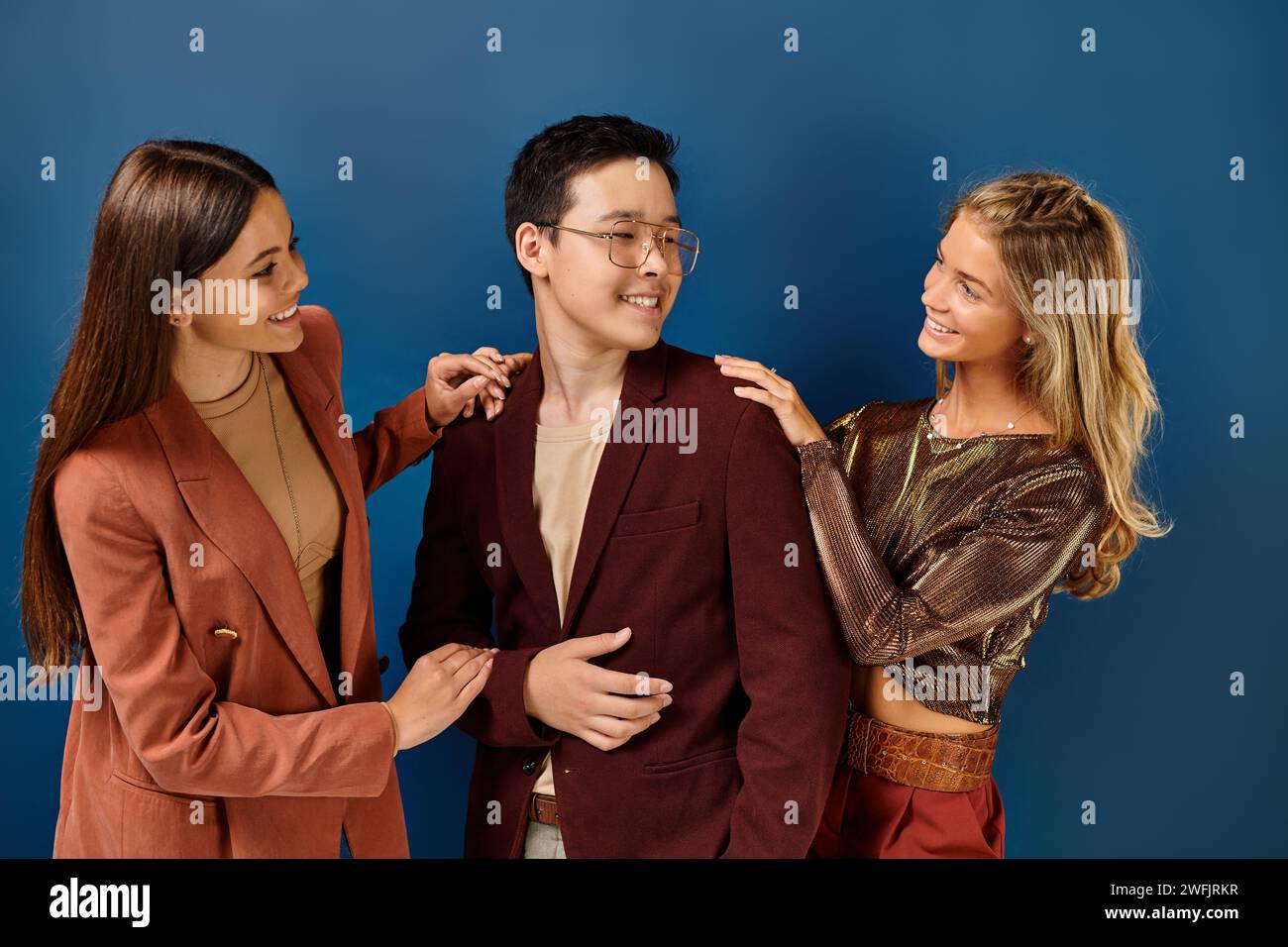 stylish multiracial teens in trendy outfits posing and smiling at each ...