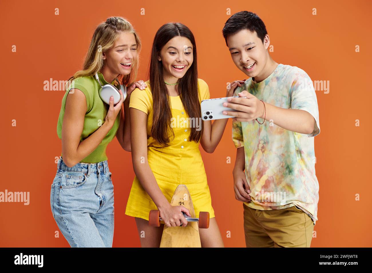 jolly adolescent diverse friends with headphones and skateboard taking ...