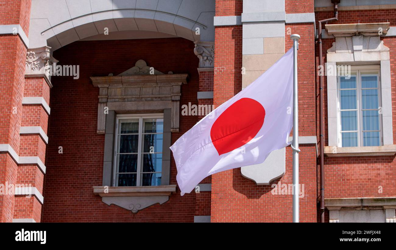 Japanese flag waving in wind at traditional building of train station ...