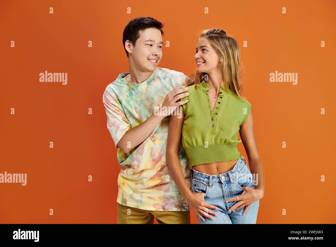 joyous interracial teens in vibrant clothes hugging and smiling at each ...