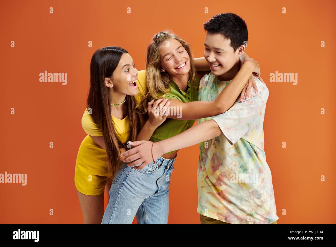 joyous multiracial teenagers in bright attires hugging each other on ...