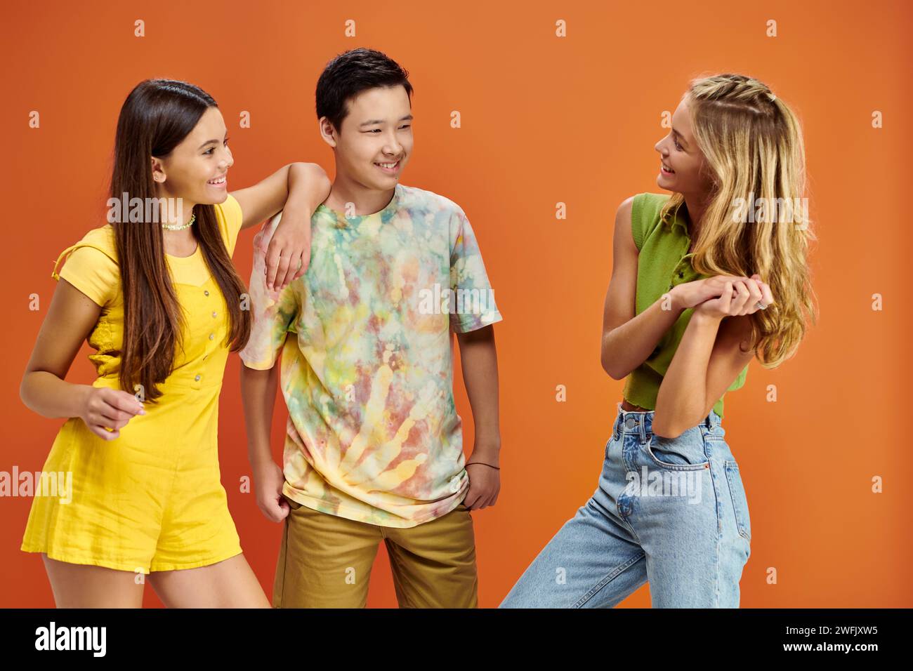 adorable jolly diverse teenagers in vibrant attires looking at each ...