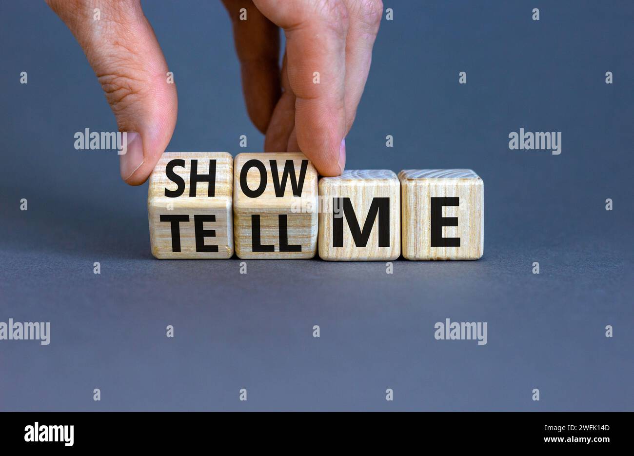 Tell or show me symbol. Businessman turns beautiful wooden cubes and ...